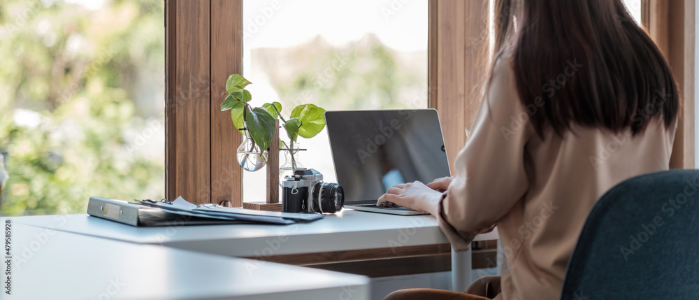 Back view of young asian businesswoman sitting on her workplace in the ...