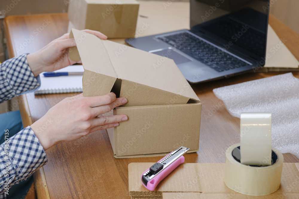 Warehouse employee packs the order of the online store in a cardboard ...