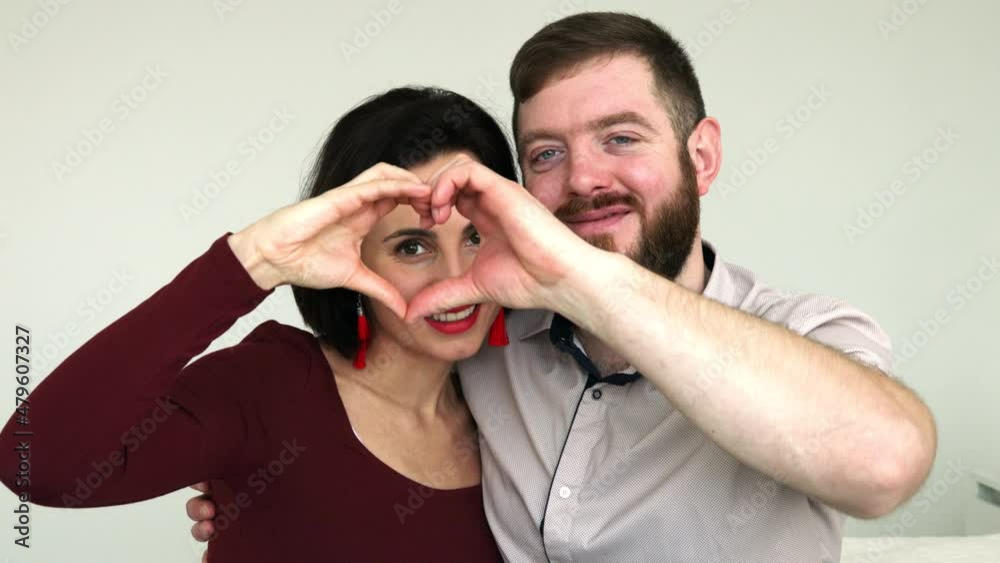 Close up happy lovely couple faces look through joined fingers making ...