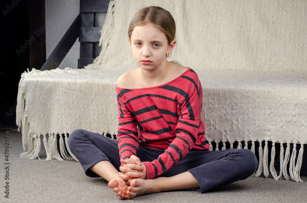 Girl's bare feet. Foot heel. Sad little girl sitting on the floor ...