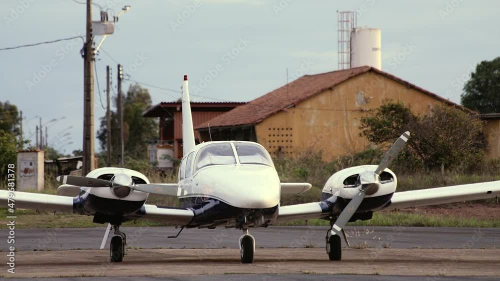 Small white and blue biplane aircraft parked on the runaway of a small ...