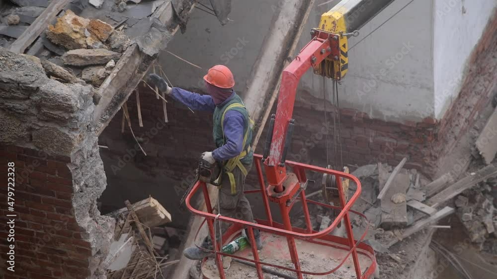 Demolition of old abandoned house, workman in orange helmet at crane ...