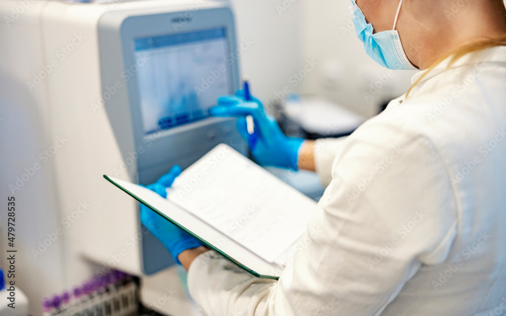Microbiology and biochemistry. A nurse standing next to a machine for ...