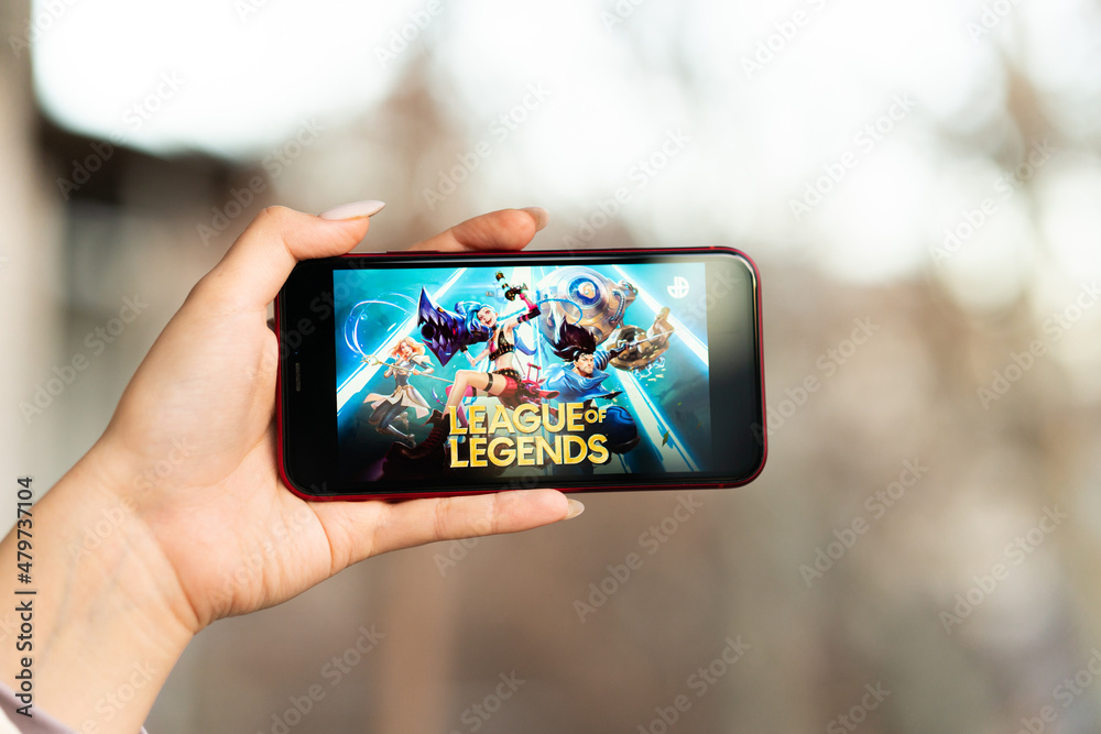 Hands holding a smartphone with League of Legends game on display ...