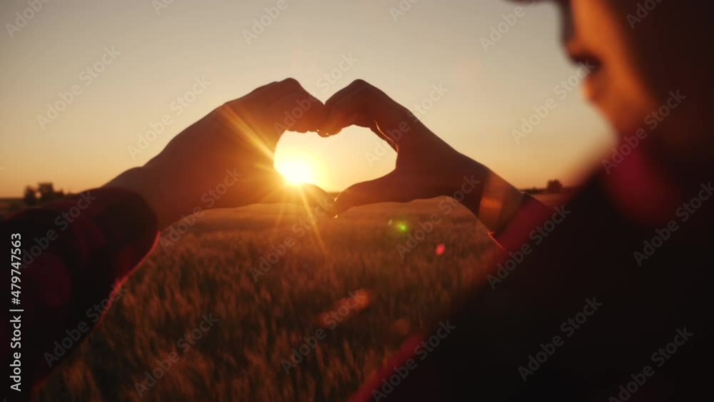 heart. girl with her hands shows a heart symbol at sunset silhouette in ...