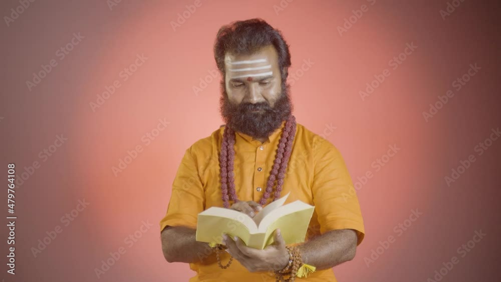 Focused holy saint reading astrology or holy vedas on studio background ...