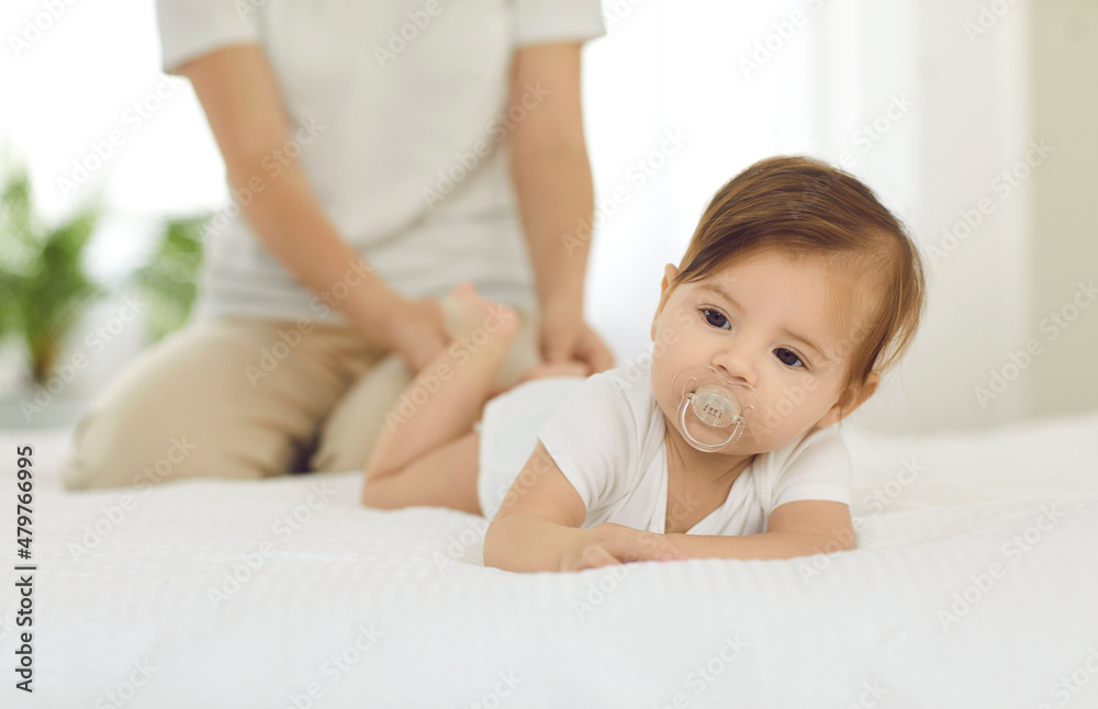 Little newborn baby lying on bed at home, mother make massage do ...