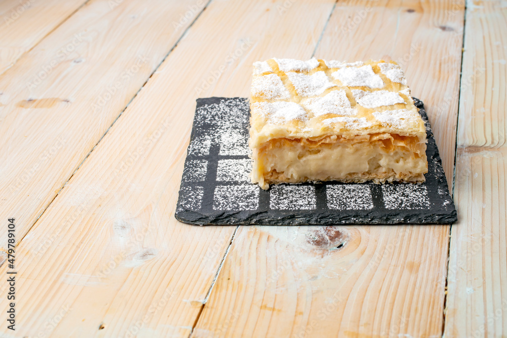 cremeschnitte or cremsnit cake on a square black stone tile texture ...