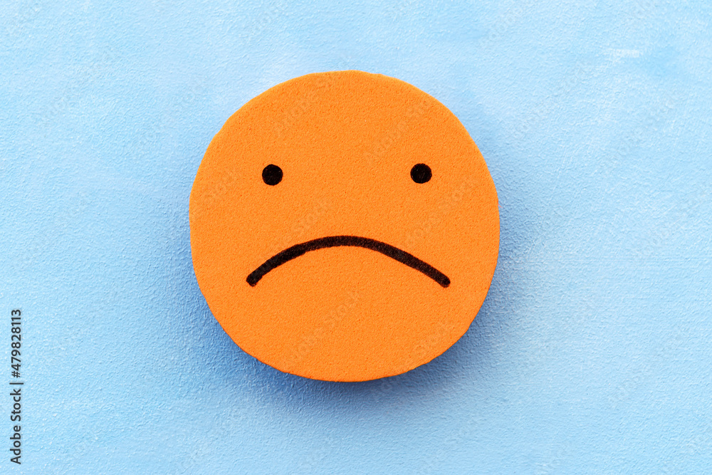 Yellow sad smiley face on a blue background. The concept of negative ...