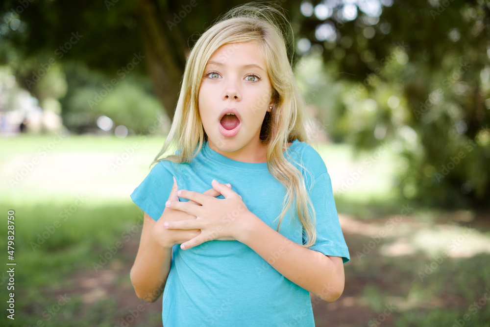 Scared Caucasian little kid girl wearing blue T-shirt standing looks ...