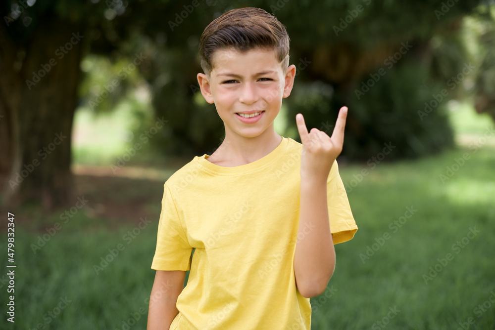 Caucasian little kid boy wearing yellow T-shirt standing outdoor doing ...