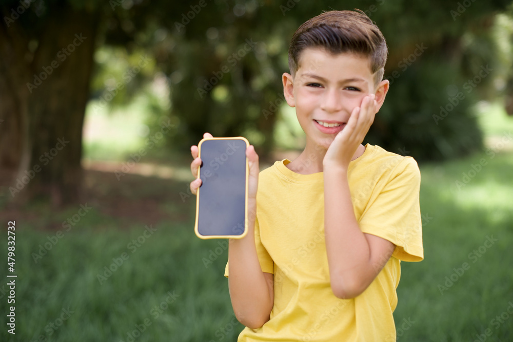 Caucasian little kid boy wearing yellow T-shirt standing outdoors hold ...