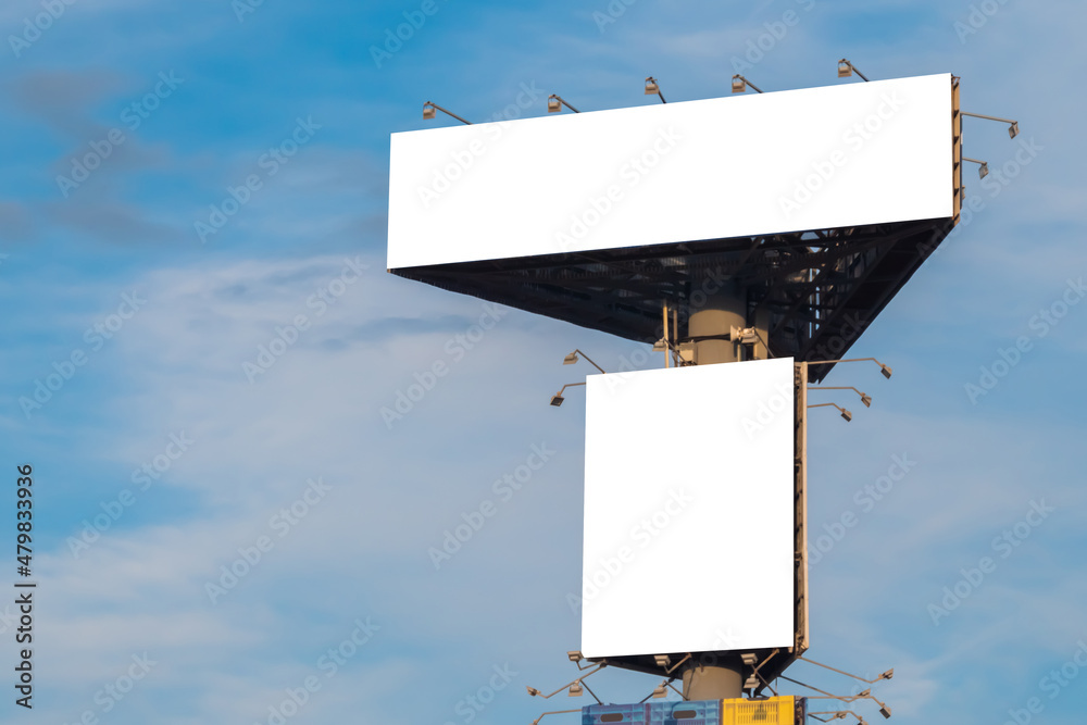 Two blank white billboards or large displays on tower against blue sky ...