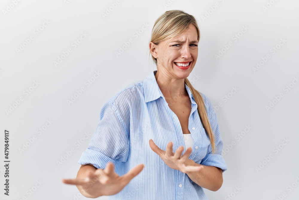 Beautiful blonde woman standing over white background disgusted ...