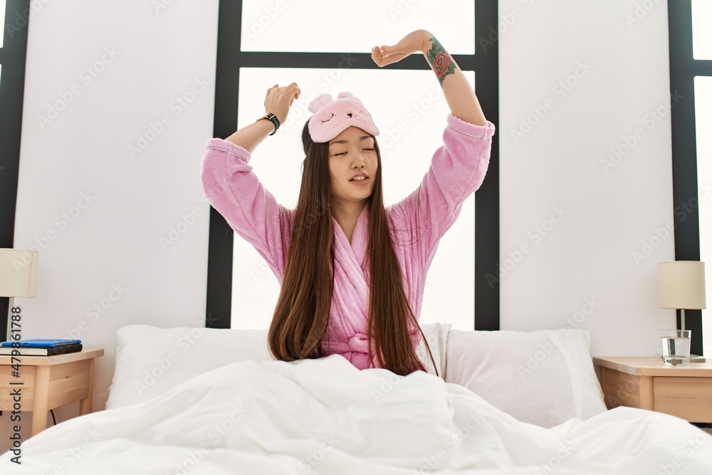 Young chinese girl waking up stretching arms at bedroom. Stock Photo ...