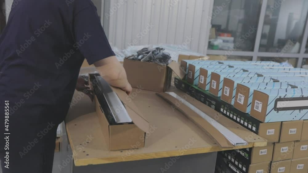 Workers pack finished products into a box. Packaging of finished goods ...