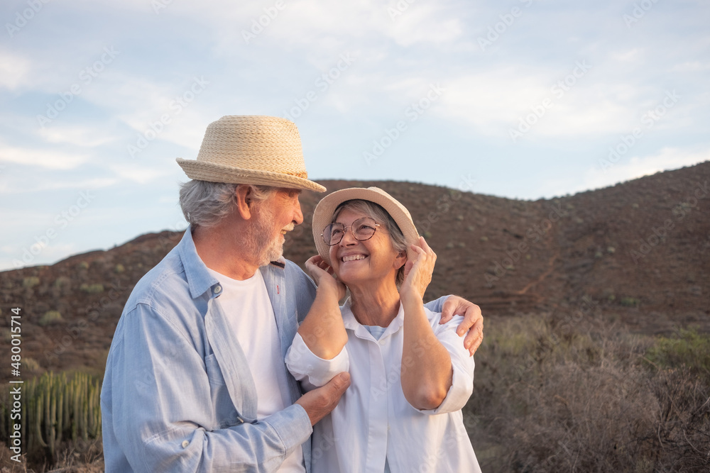 Cheerful mature senior couple enjoying healthy activity in outdoor mountain excursion at sunset ...