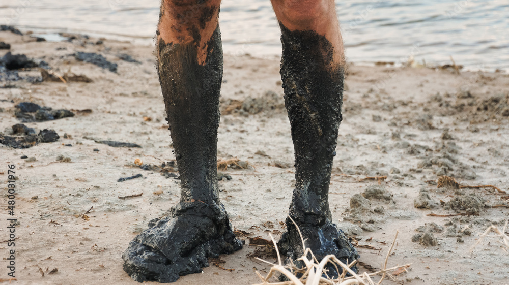 Male feet in therapeutic mud. Mud therapy. Mud bathing. Bath in the mud ...