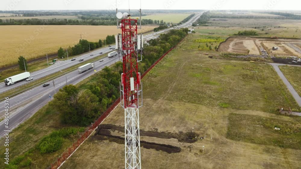 Telecommunication tower 5G near highway with car traffic. Telecom tower antenna and satellite ...