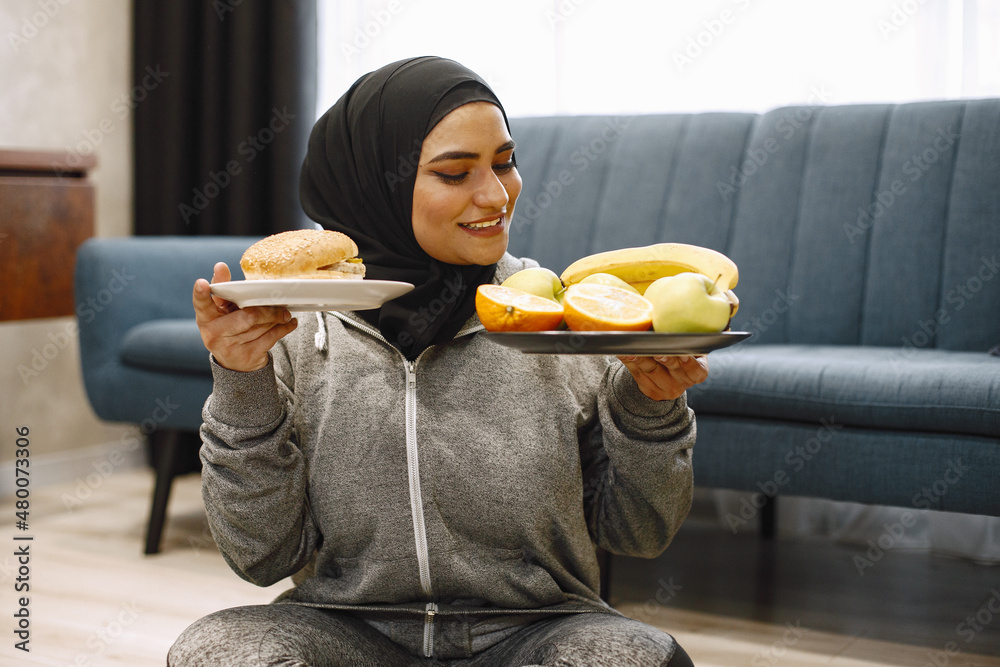 Arab woman choosing between healthy and unhealthy eating. Stock Photo ...