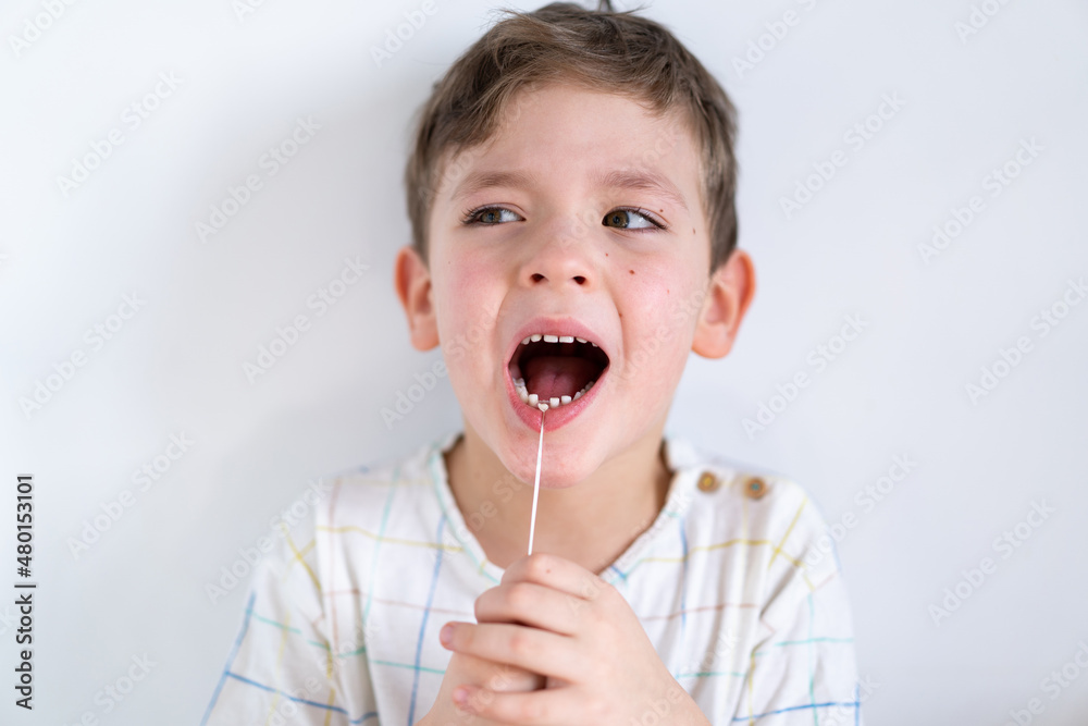 Cute boy pulling loose tooth using a dental floss. The boy's first milk ...