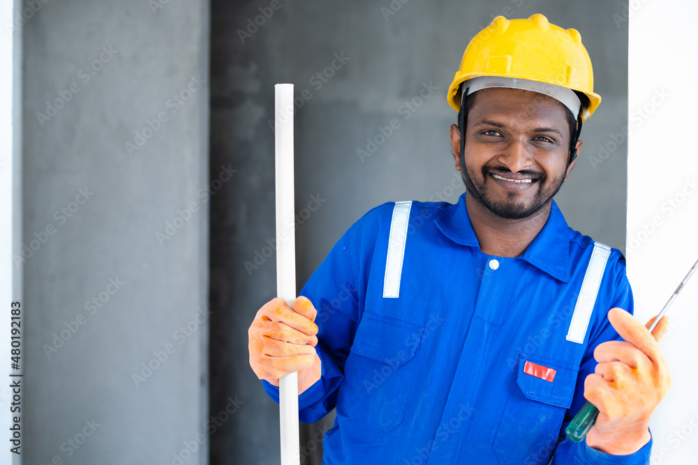 Smiling plumber with pipe and plumbing tool in hand showing thumb by ...