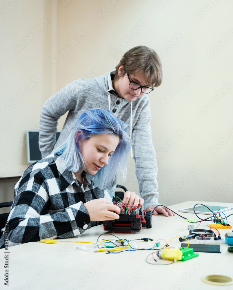 School student making robotic cars. Teenager girl and boy at robotics ...