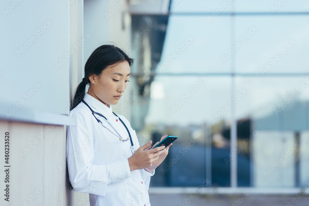 Portrait young Asian doctor woman or paramedic stands exhausted on a ...