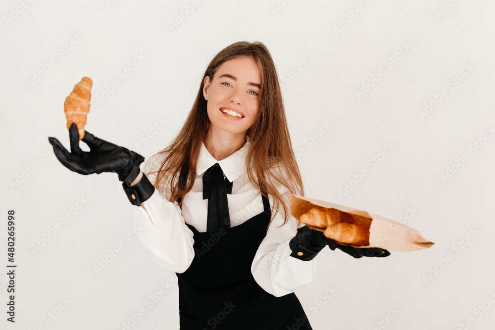 Laughing waitress in a uniform posing with fresh croissants, ready to ...