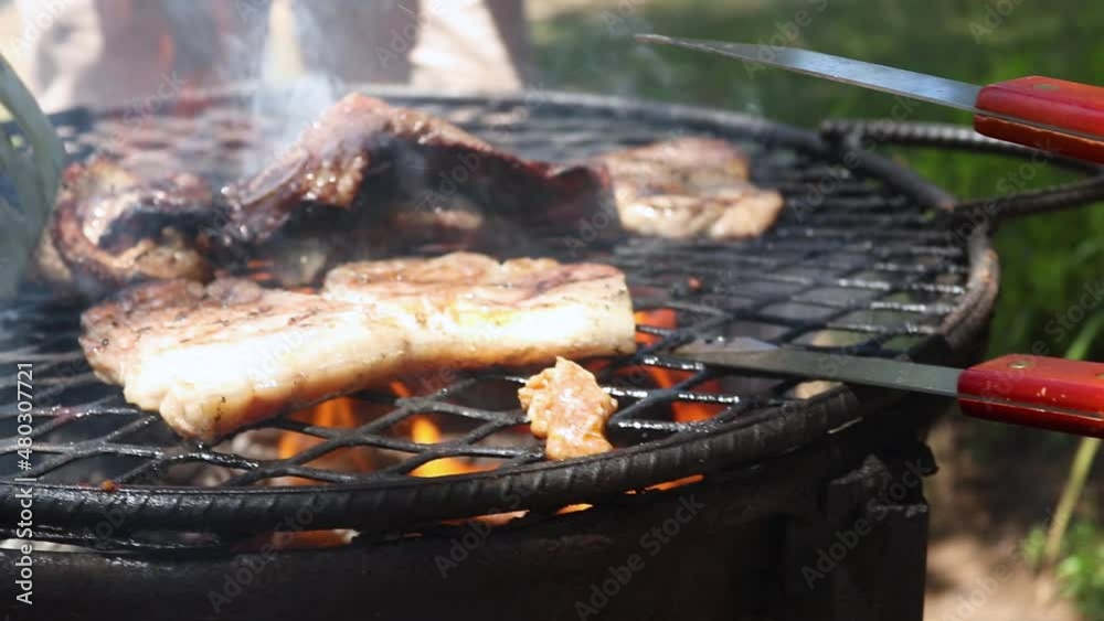 Close up view of an open fire, with people cooking meat on top known as ...