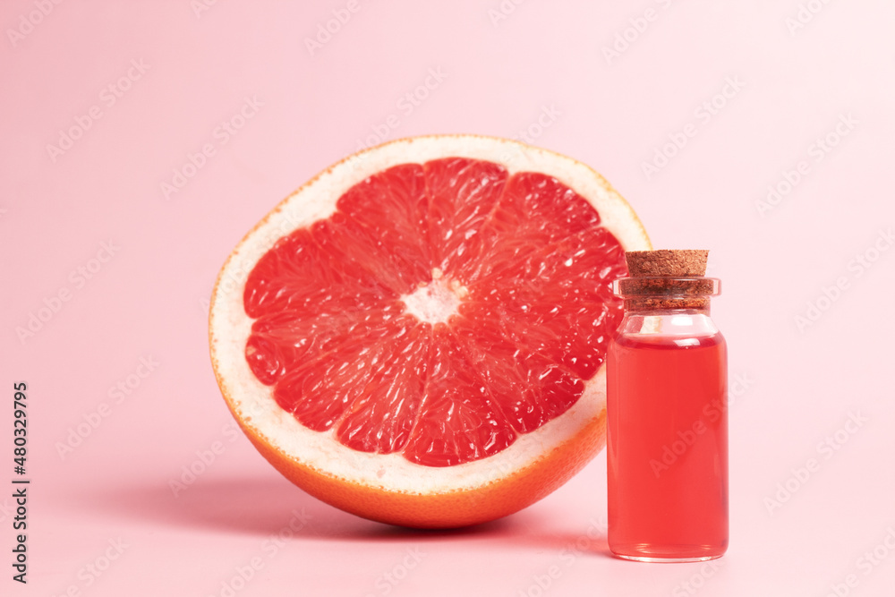 Little glass vial of aroma essential oil wich grapefruit fresh slice ...