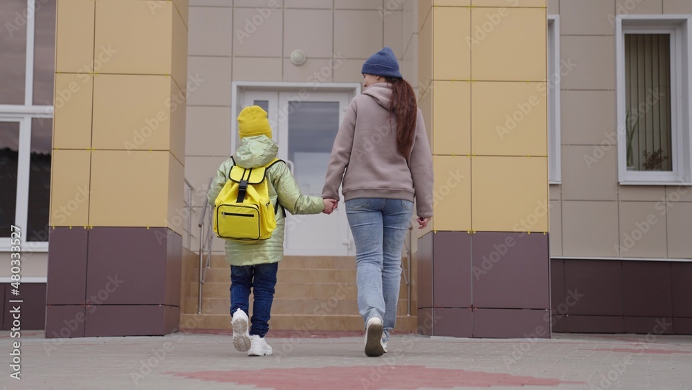 affectionate mother leads the child back to school, to teach first ...
