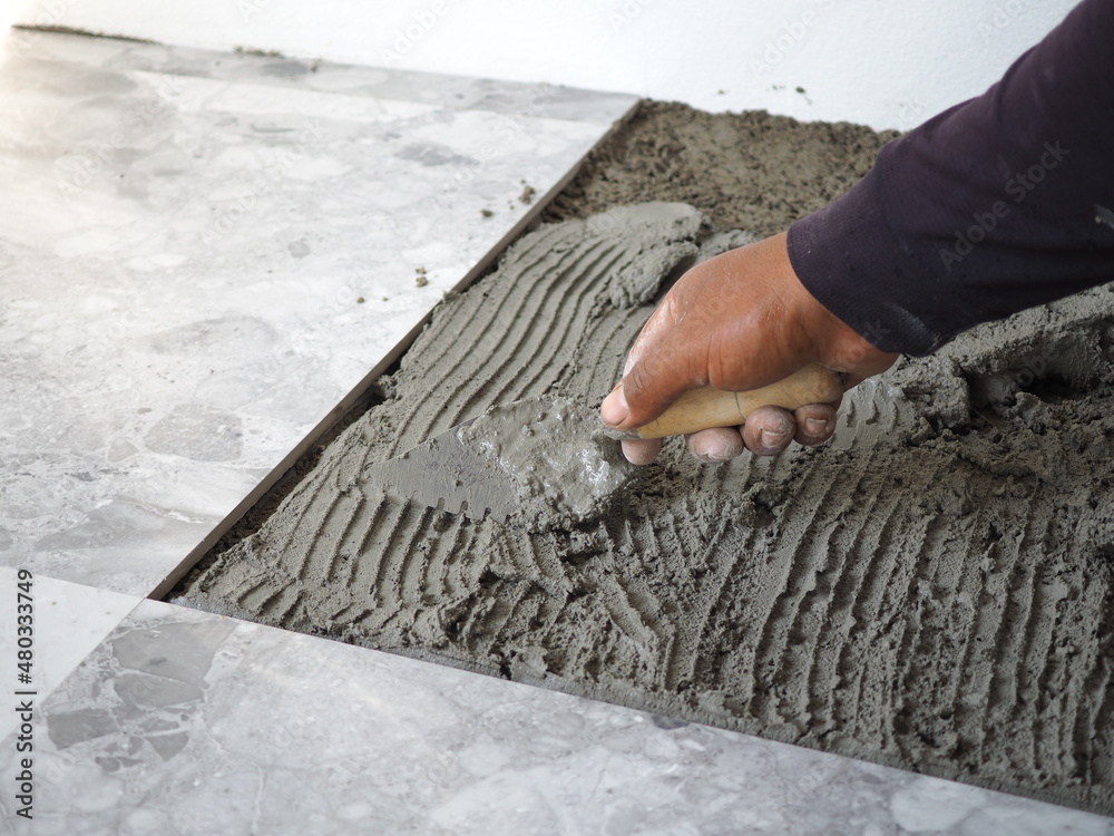 Laying floor ceramic tile. construction workers laying tile over ...