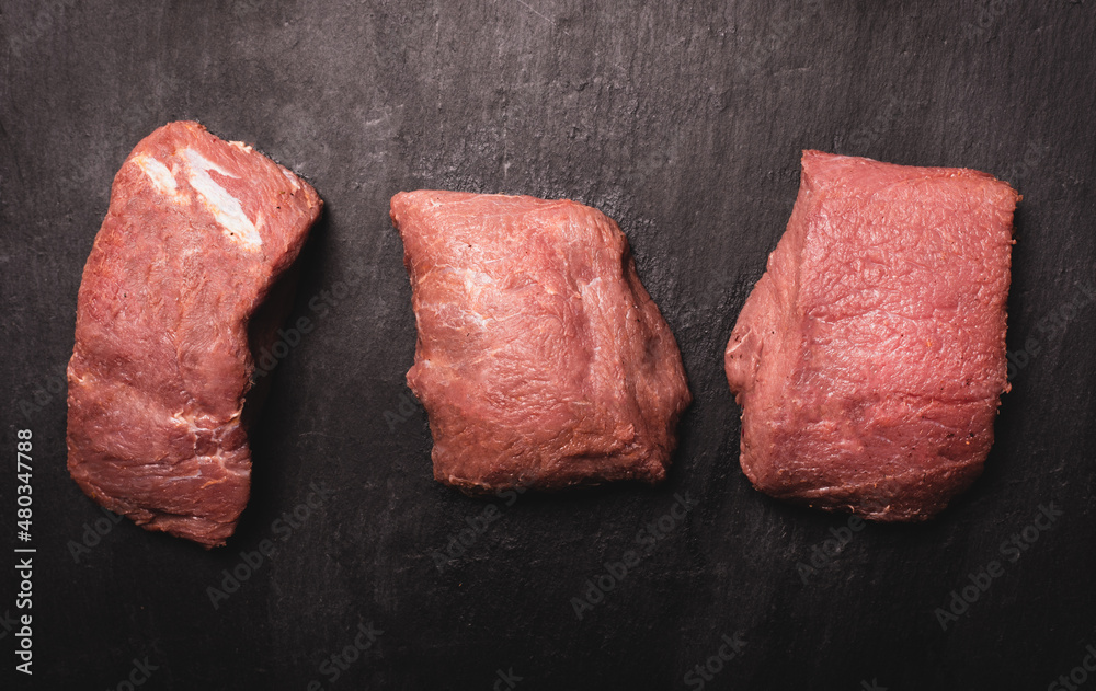 Raw game meat, beef, top view. Pieces of meat on black stone background ...
