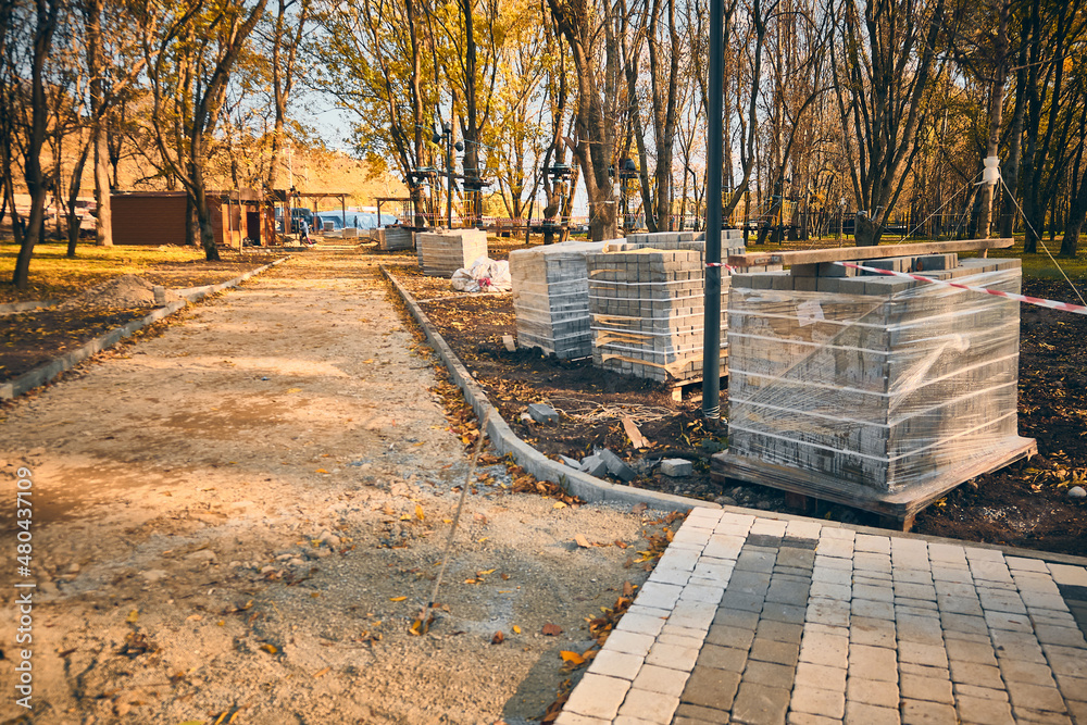 Stacked wooden pallets and laid paving tiles. Public park pavement ...