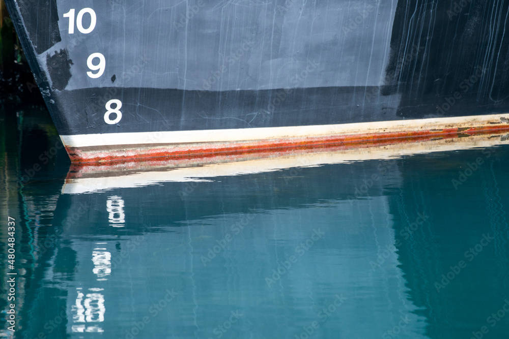 A navy blue ship with waterline marks painted white and red in color ...