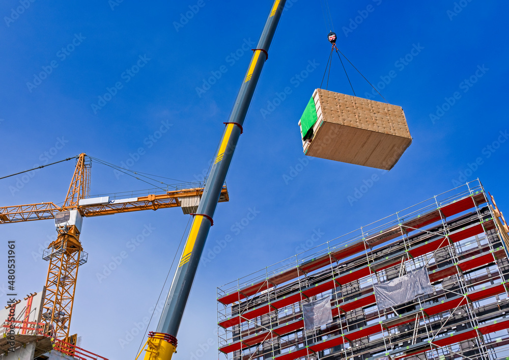 Crane lifting a prefabricated wooden building module to its position in ...