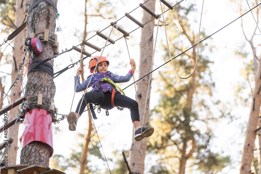 Little girl is standing on a rope, holding a rope with his hands. A ...