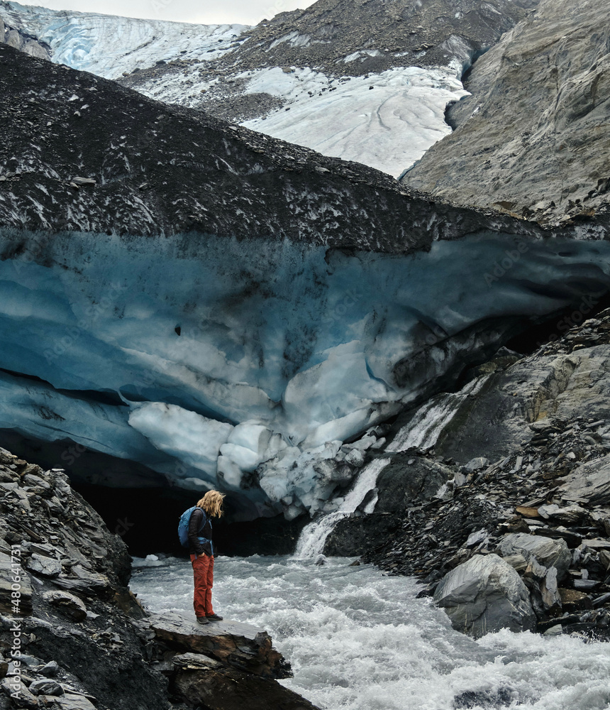Adventurous Ice Climber Woman walking in front of blue glacier on ...