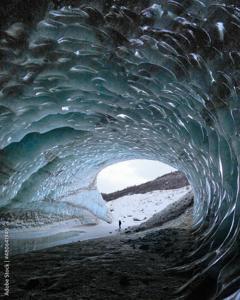 Adventurous Ice Climber Woman walking in an ice cave on a glacier in ...