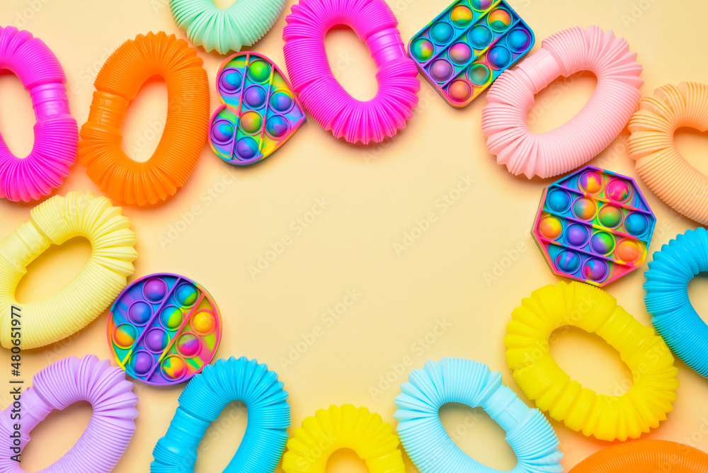 Frame made of colorful Pop Tubes and Pop it fidget toys on yellow ...