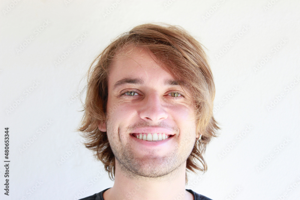 Young man with green eyes smiling candid. Young man with long blonde ...