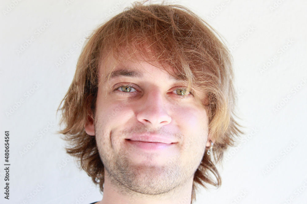 Young man with green eyes smiling candid. Young man with long blonde ...