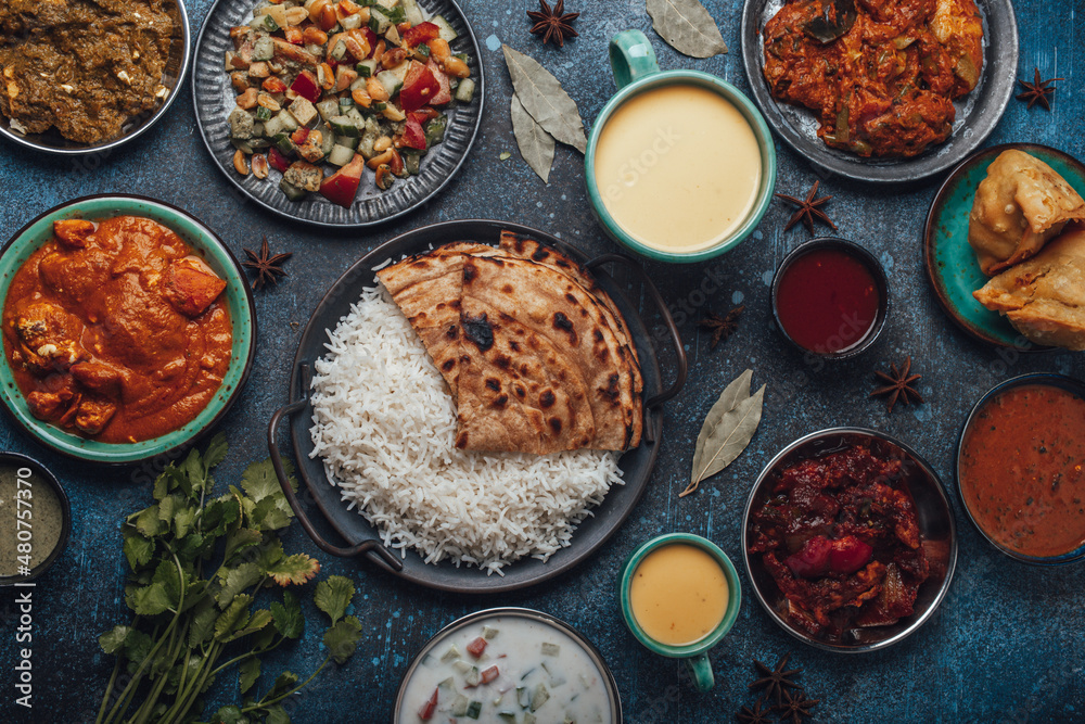 Assorted Indian ethnic food buffet on rustic concrete table from above ...