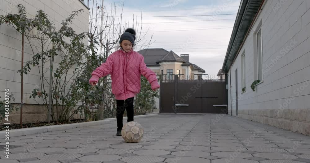 Child with a soccer ball. A teenage girl hits a football with a sword ...