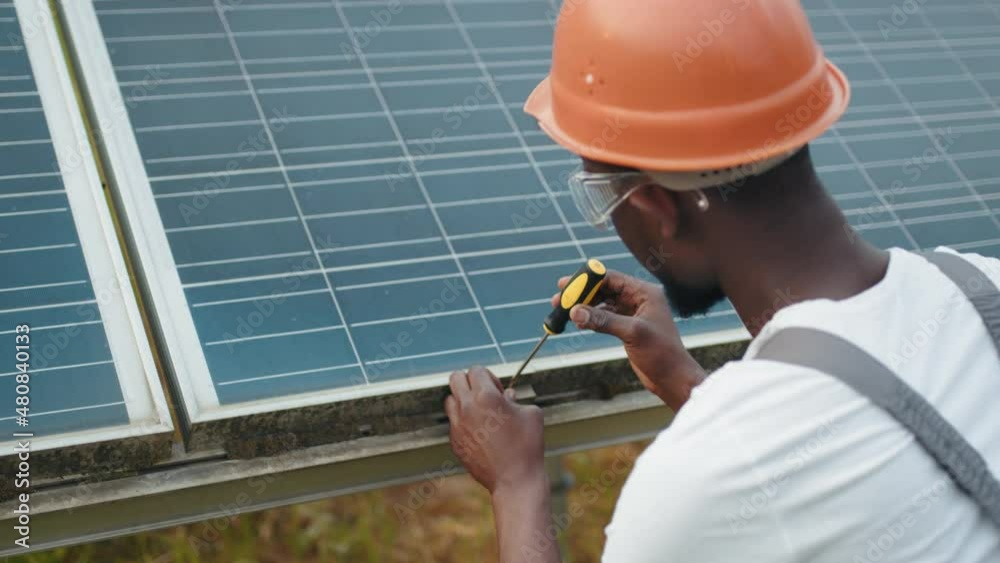 African american technician in helmet and overalls fixing solar panels ...
