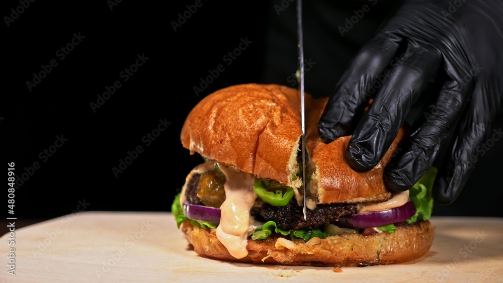 Cut craft burger is cooking on black background. Consist sauce salsa ...