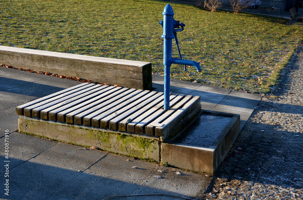 blue metal retro well with polished elegant wooden lid. water flows ...