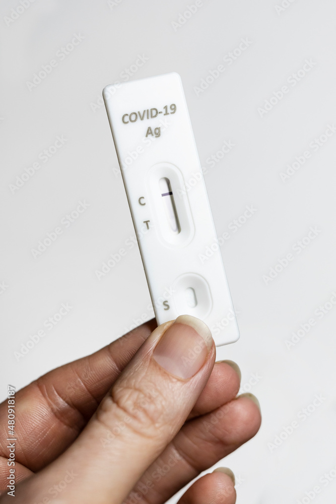 Rapid antigen test held by left hand with negative result at home in ...