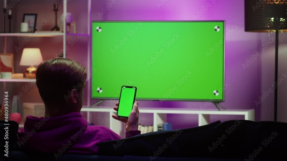 Man watching television in living room. Young guy sitting on sofa ...
